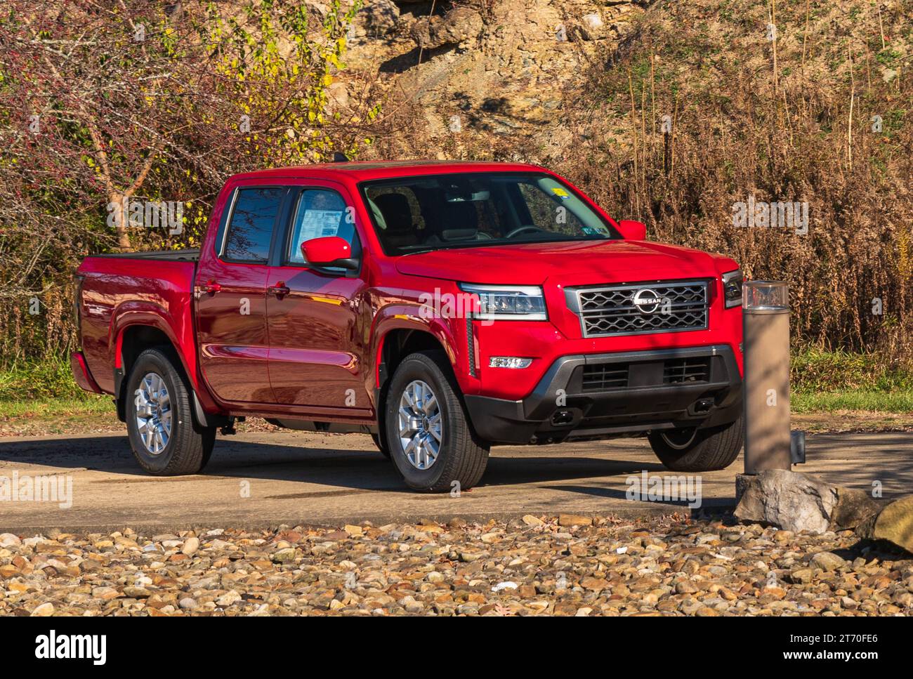 A new, red Nissan four door pickup truck for sale at a dealership in ...