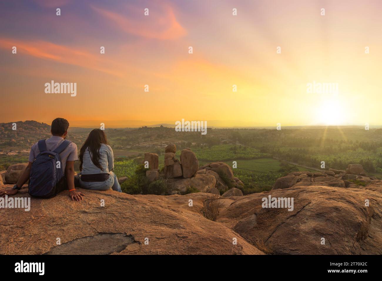 Tourist couple enjoy sunset view from top a hill at Hampi Karnataka ...