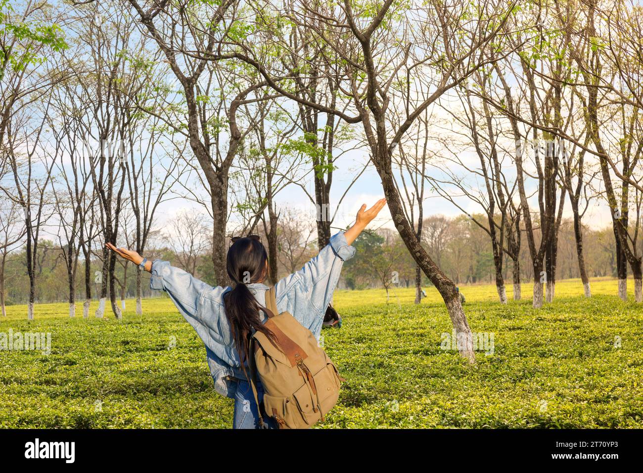 Young female tourist exults in joy with raised arms while standing in a ...