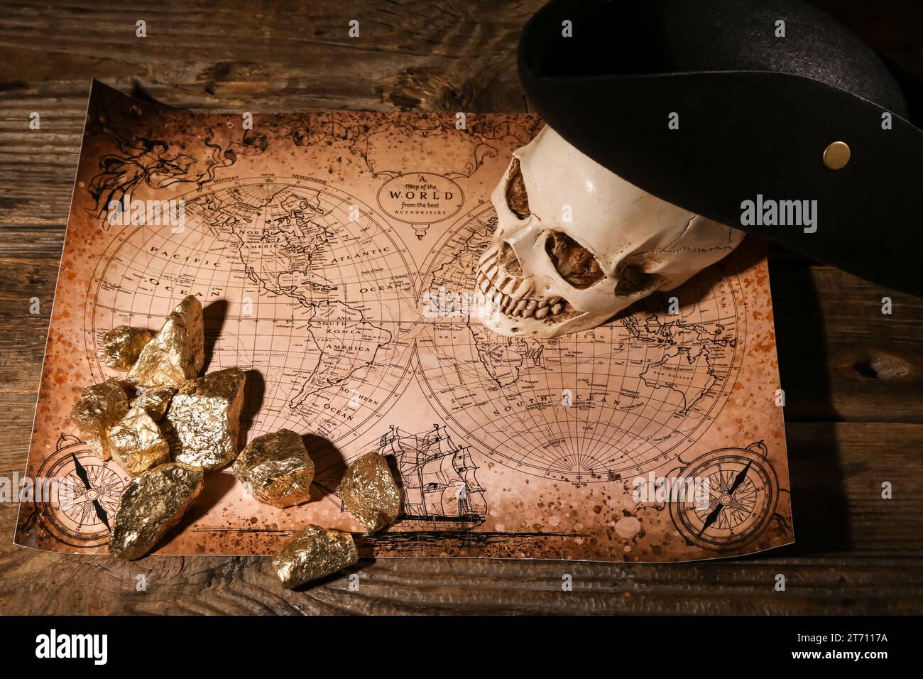 Human skull with world map, pirate hat and golden nuggets on brown ...