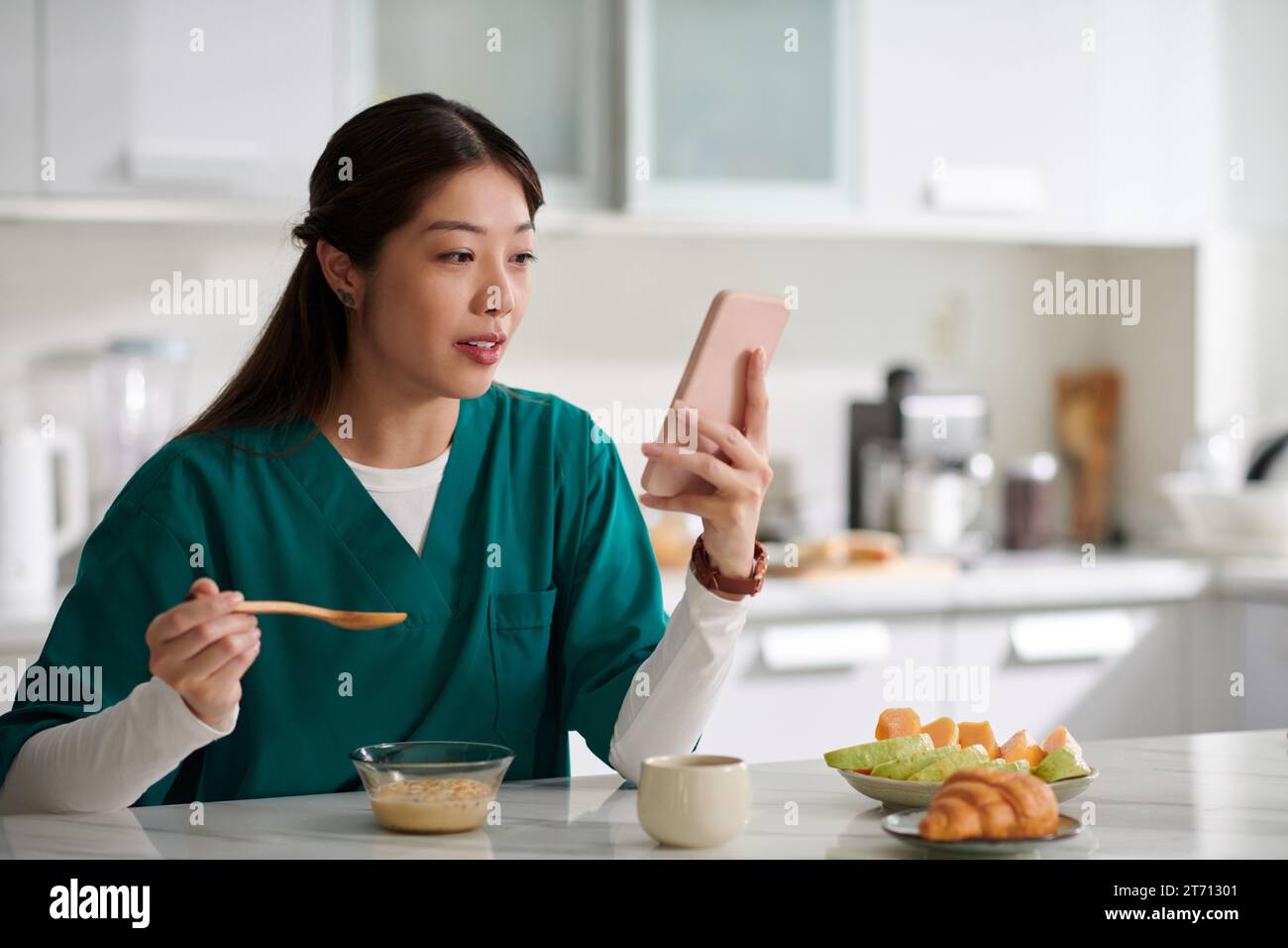 Medical nurse eating muesli for breakfast and reading news on social ...