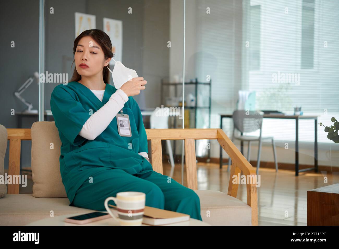 Exhausted nurse sitting on bench and taking off medical mask Stock ...
