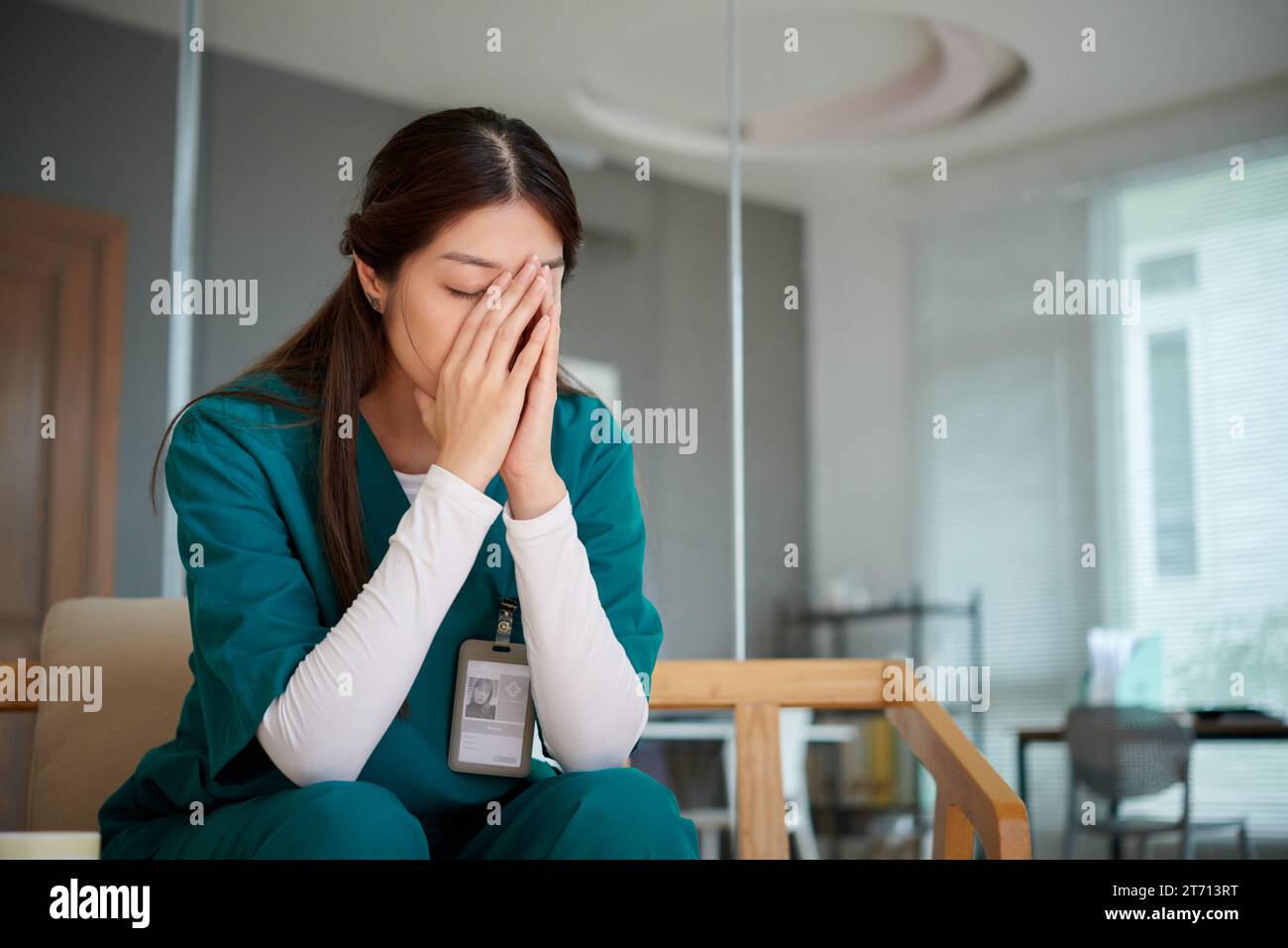Tired young medical nurse crying in hospital lounge area after ...