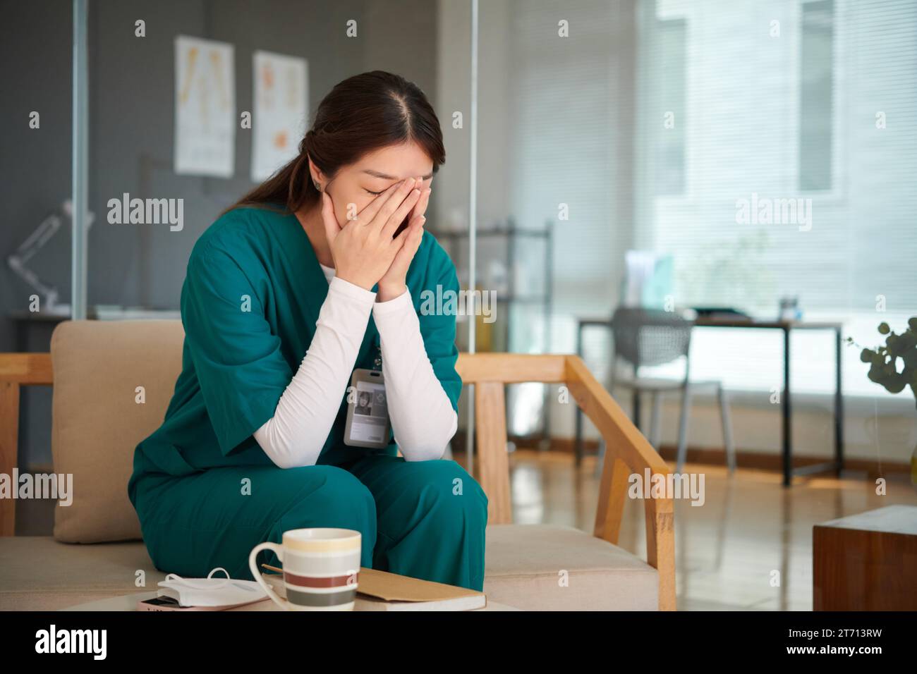 Medical nurse sitting on bench in lounge area and crying after loosing ...