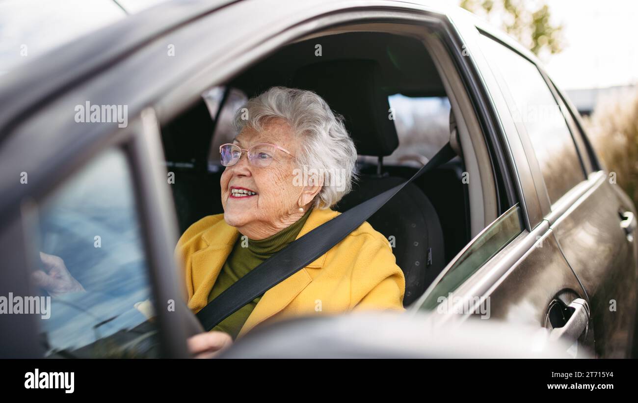Happy senior woman driving car alone, enjoying car ride. Safe driving ...