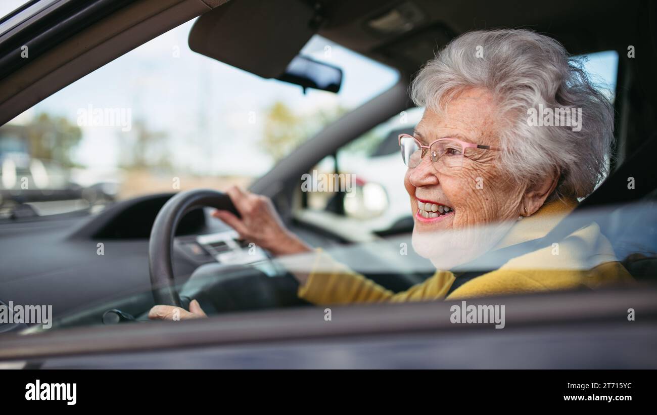 Happy senior woman driving car alone, enjoying car ride. Safe driving ...