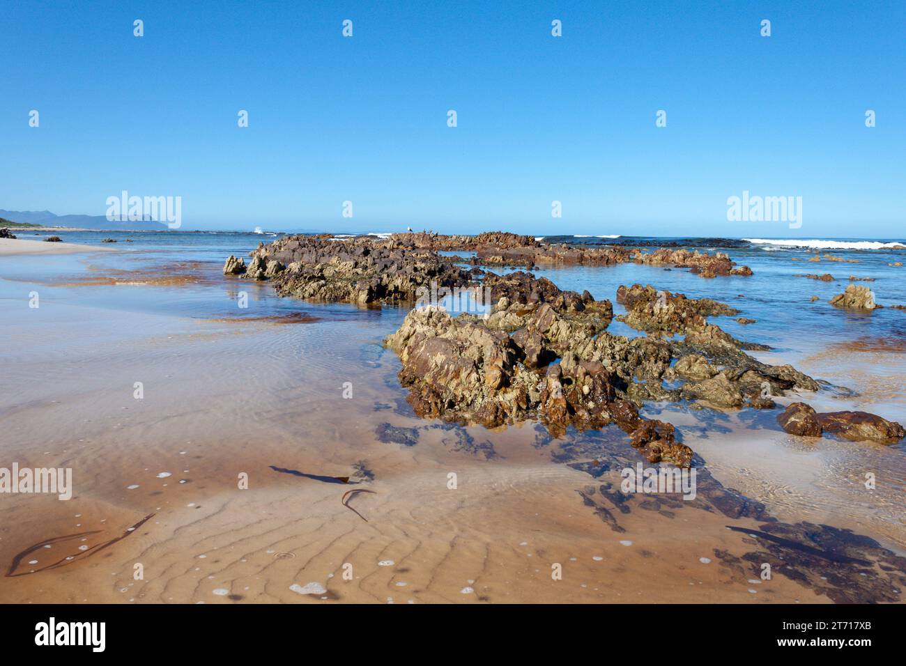 A scenic beach landscape with an expanse of small rocks, sand, and ...