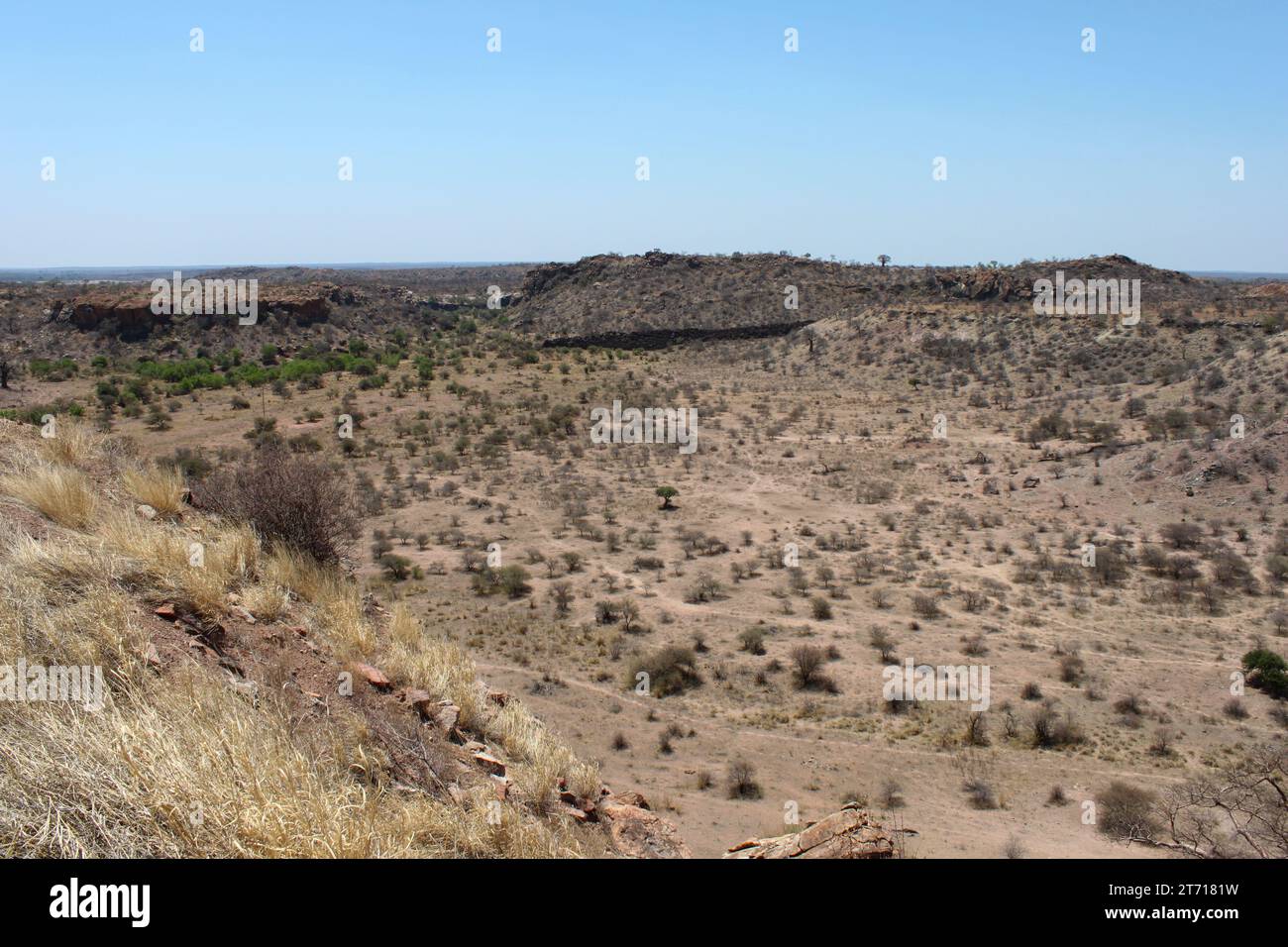 A scenic outdoor landscape with large grass-covered rocks and a hill in ...