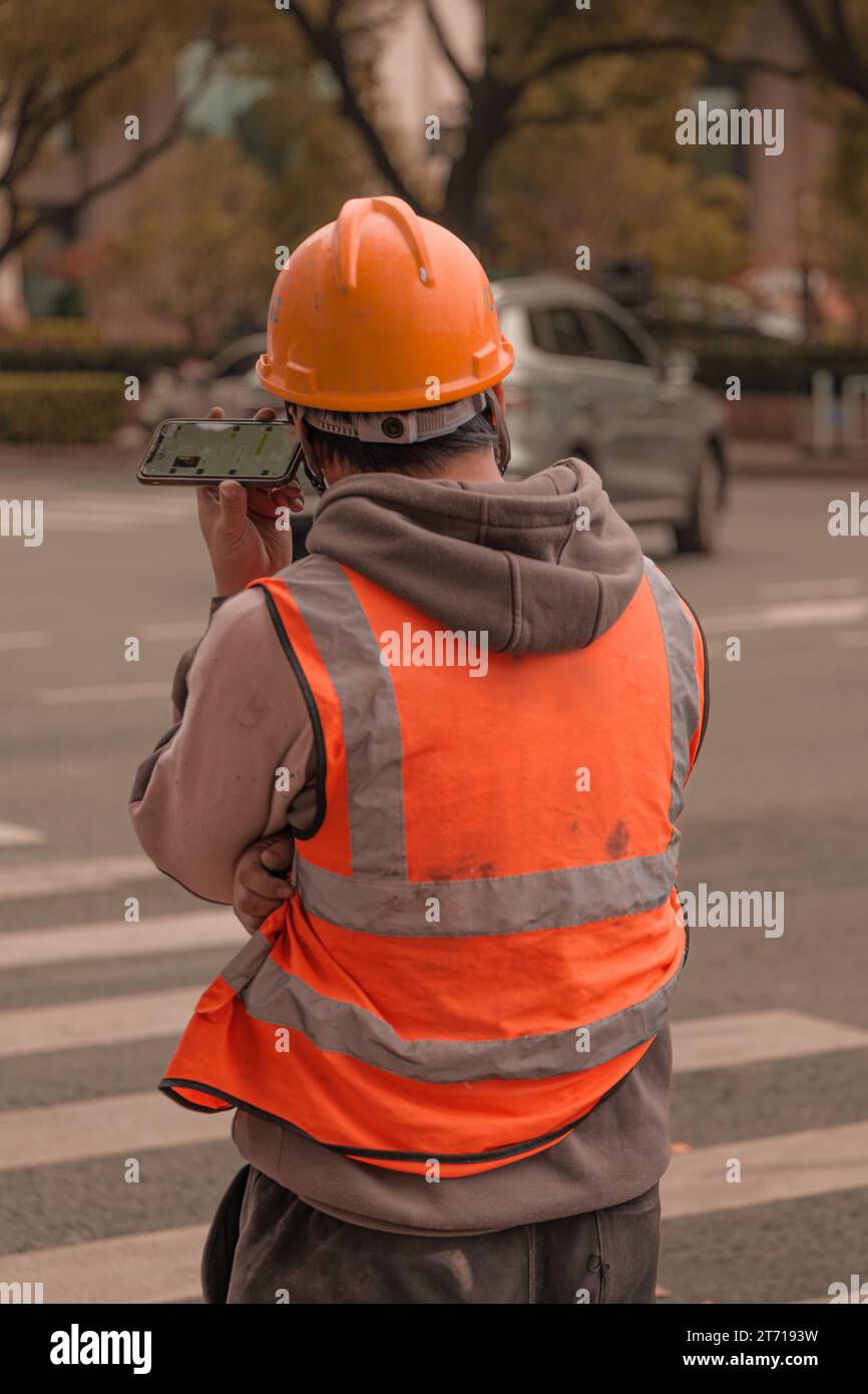 A construction worker in a safety helmet standing on a city street ...