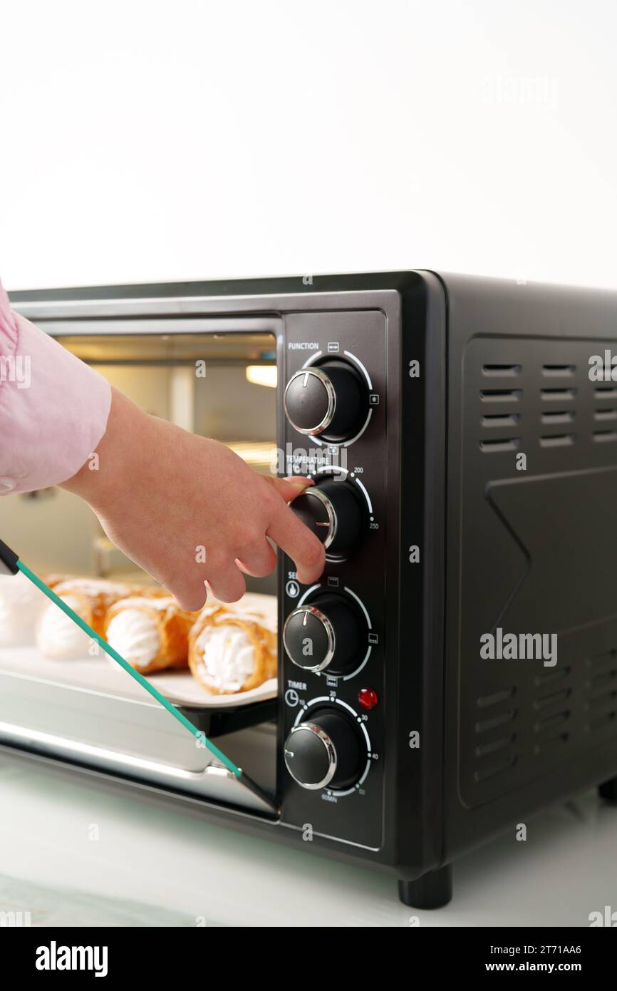 Woman's hands taking fresh bakery out of mini oven Stock Photo - Alamy