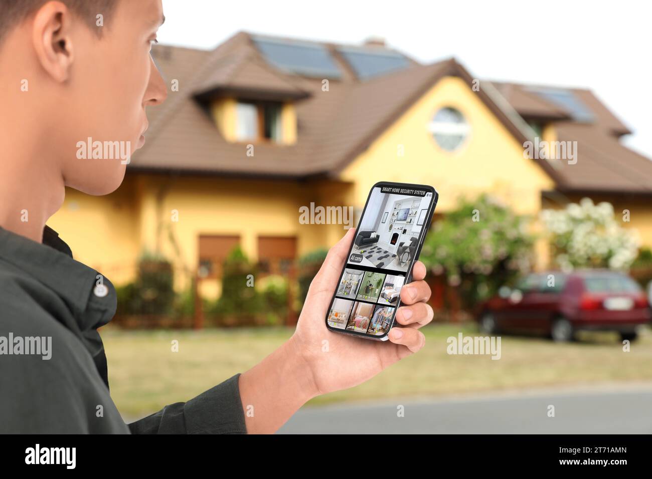 Man using smart home security system on smartphone near house outdoors ...