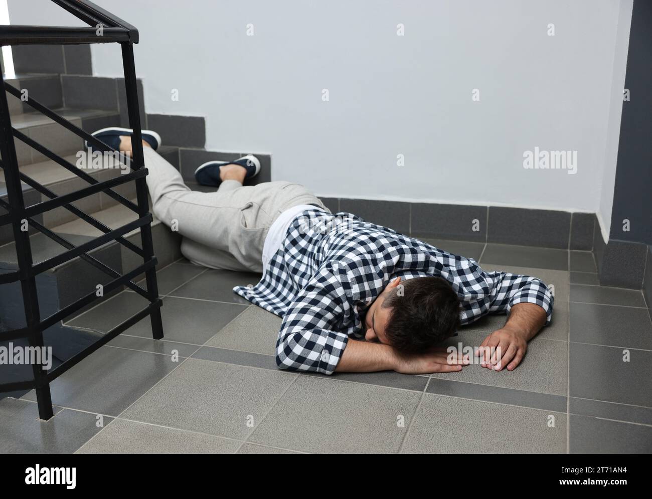 Unconscious man lying on floor after falling down stairs indoors Stock ...