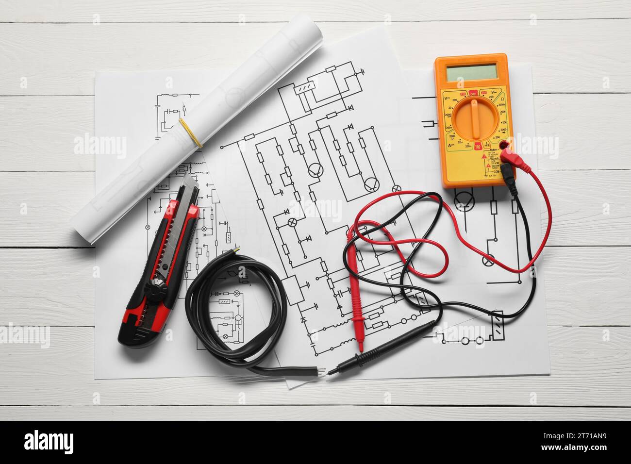 Wiring diagrams, wires and digital multimeter on white wooden table ...
