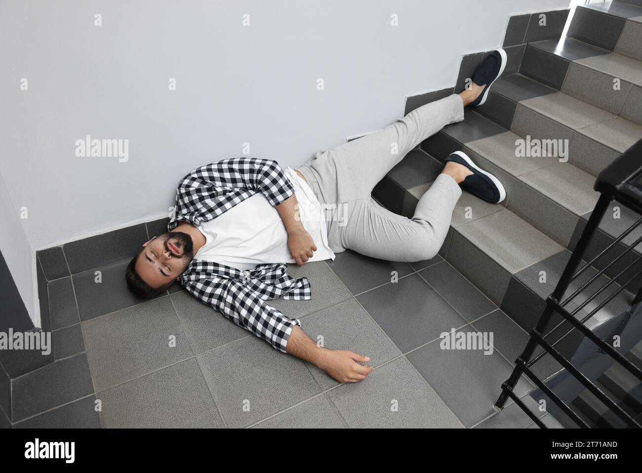Unconscious man lying on floor after falling down stairs indoors Stock ...