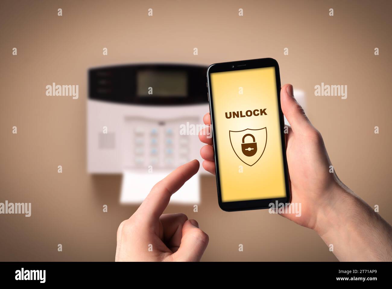 Man operating home alarm system via mobile phone against beige wall ...