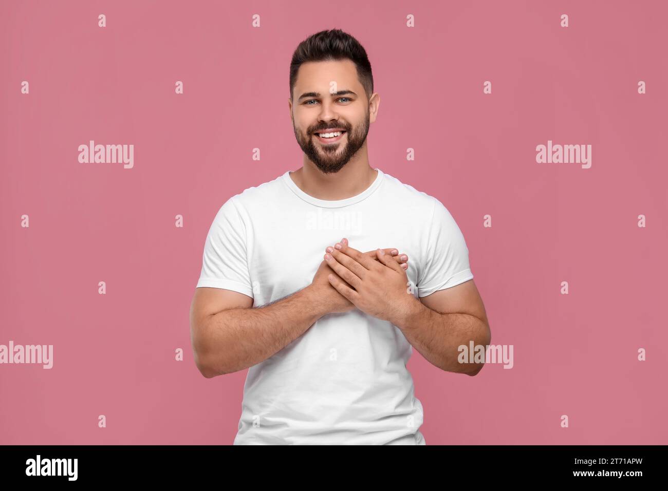 Thank you gesture. Handsome grateful man holding hands near heart pink ...