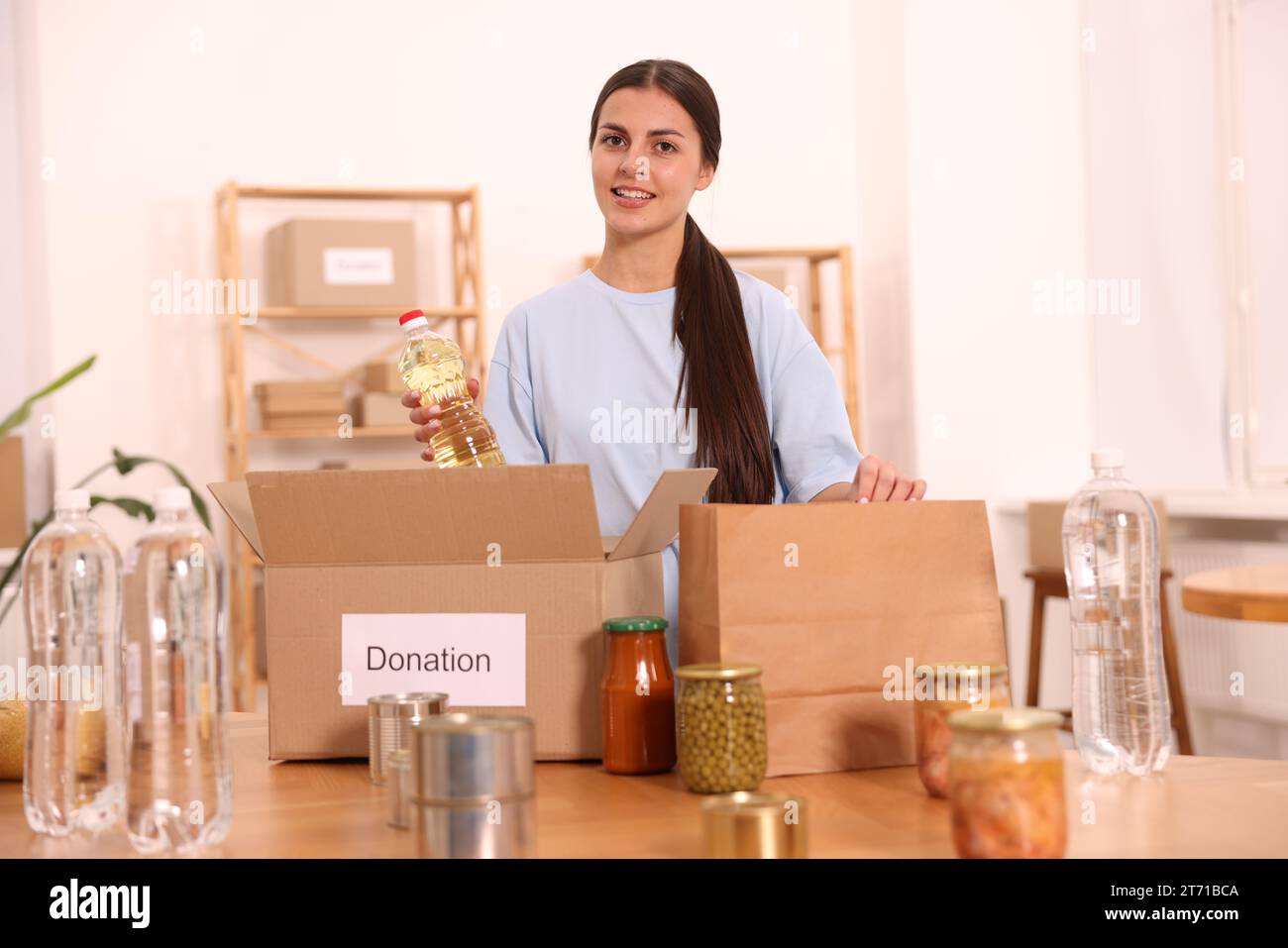 Volunteer packing food products at table in warehouse Stock Photo - Alamy
