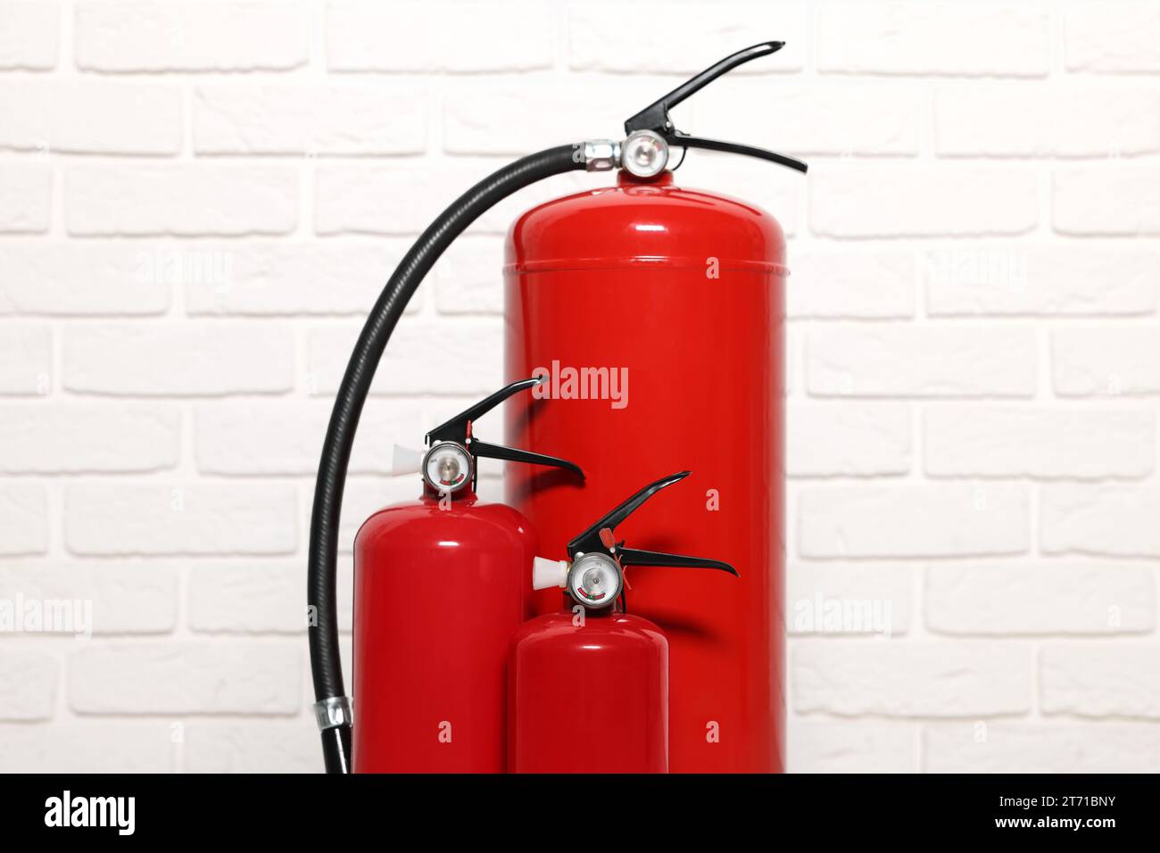 Red fire extinguishers near white brick wall Stock Photo - Alamy