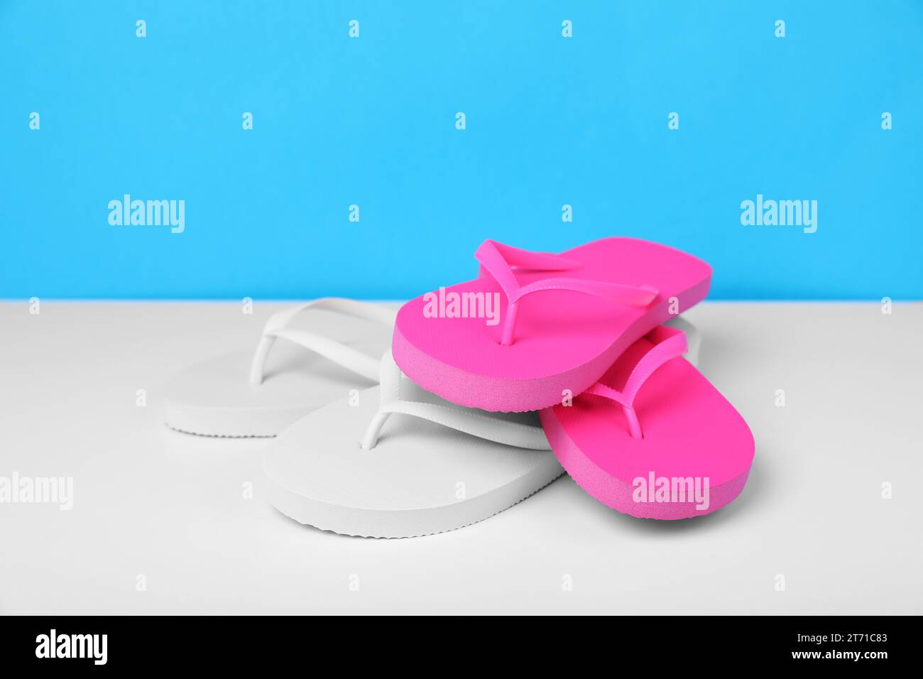 Different flip flops on white table against light blue background Stock ...
