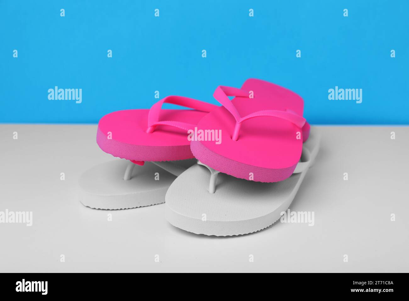 Different flip flops on white table against light blue background Stock ...