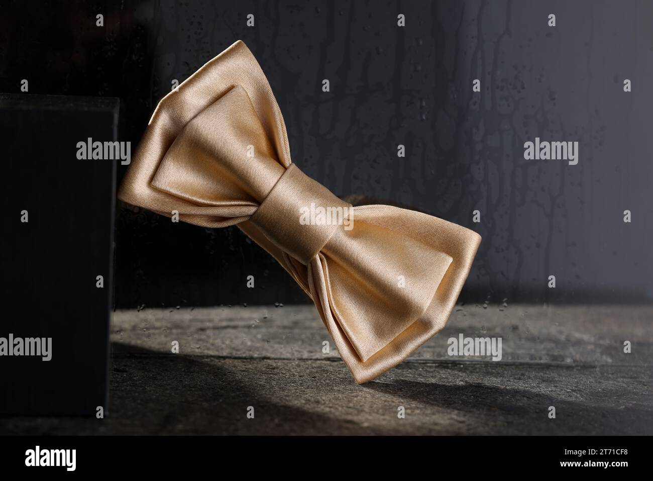 Stylish presentation of pale yellow bow tie on gray textured table ...
