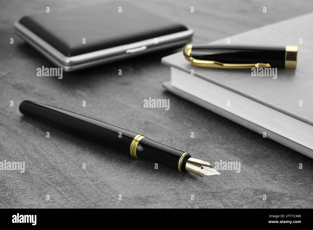 Stylish black fountain pen, notebook and cigarette case on grey ...