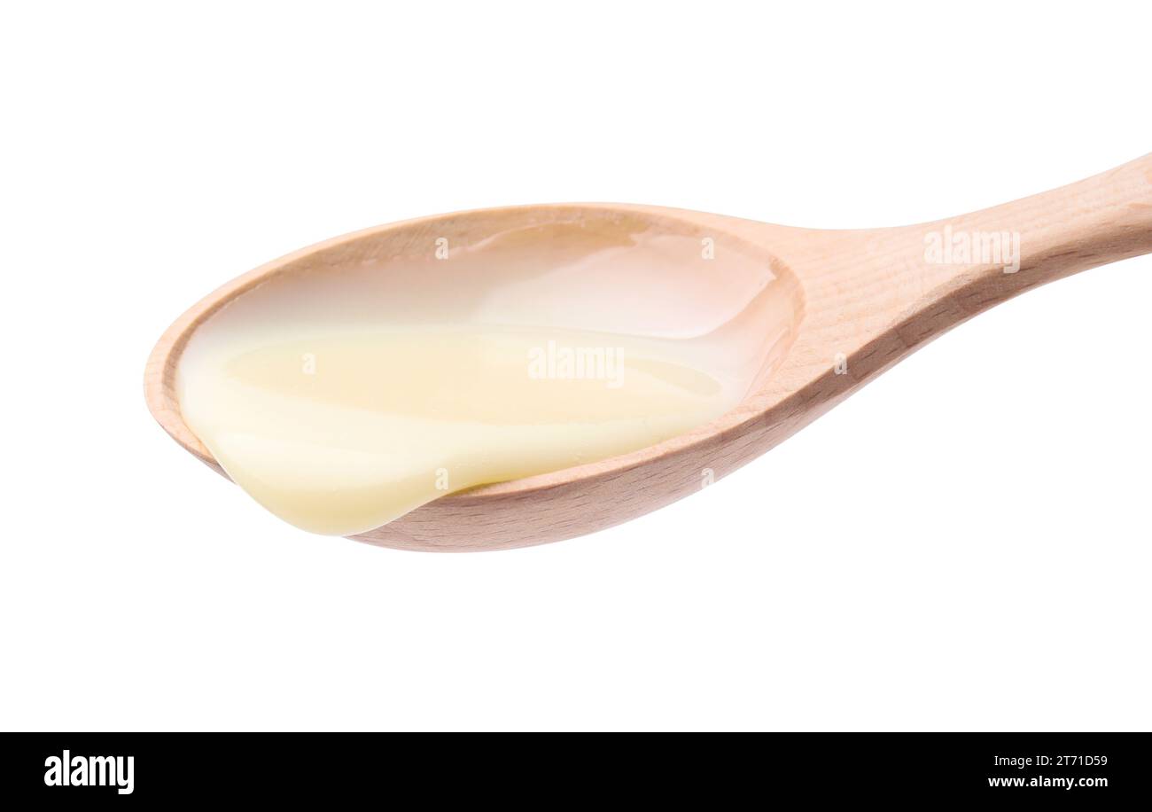 Wooden spoon with condensed milk isolated on white Stock Photo - Alamy