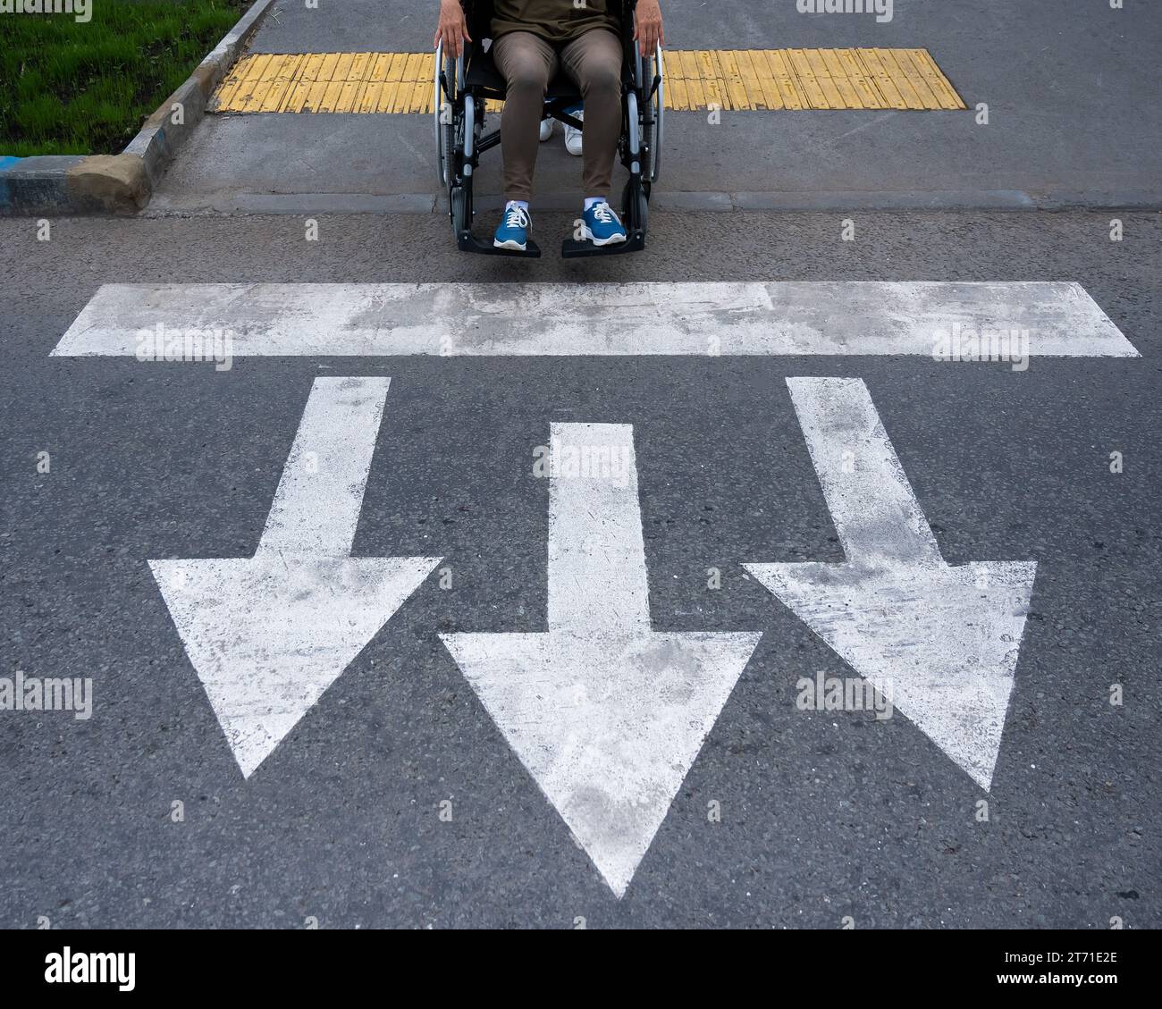 An elderly woman in a wheelchair is about to cross the road at a ...