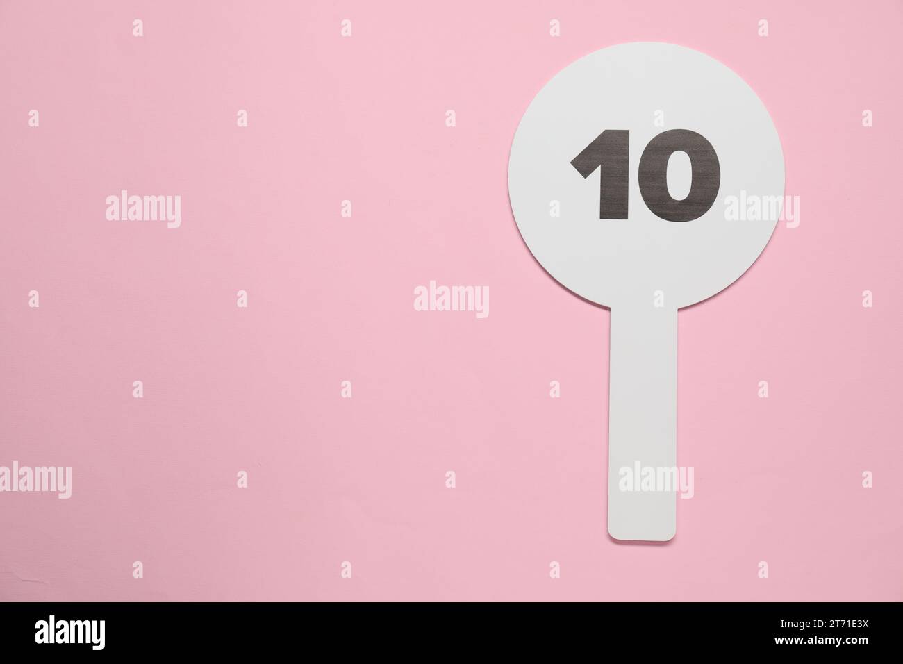 Auction paddle with number 10 on pink background, top view. Space for ...