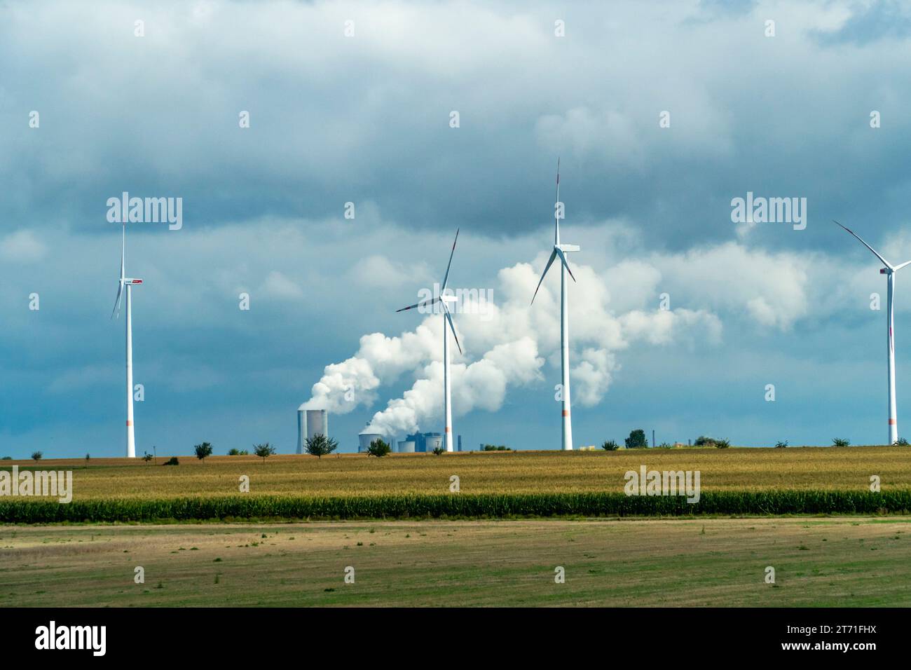 Wind turbines and industrial pipes with smoke coming out of them on a ...