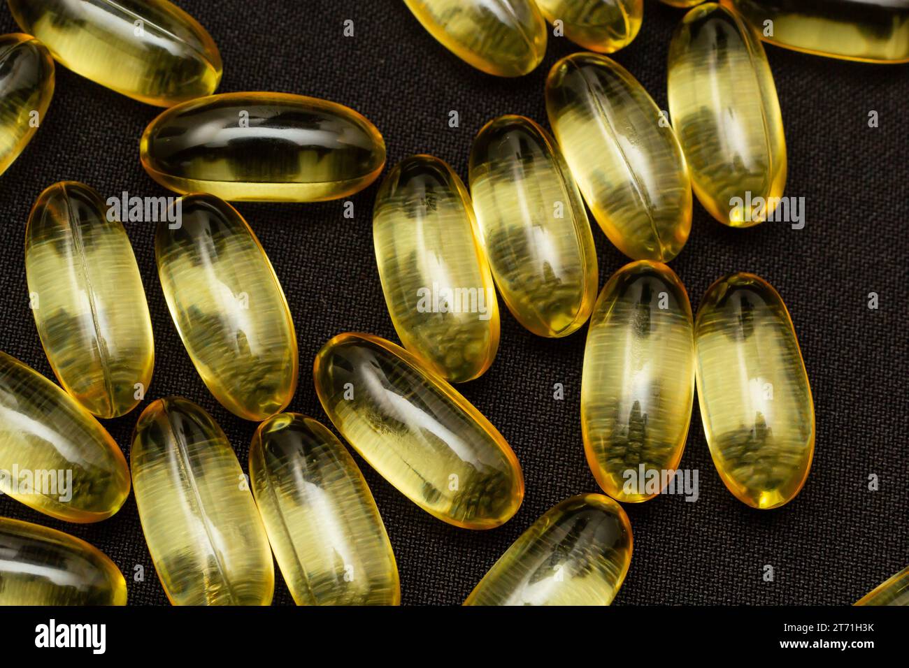 Macro Close up of Omega 3 gel capsule on a reflective black background ...