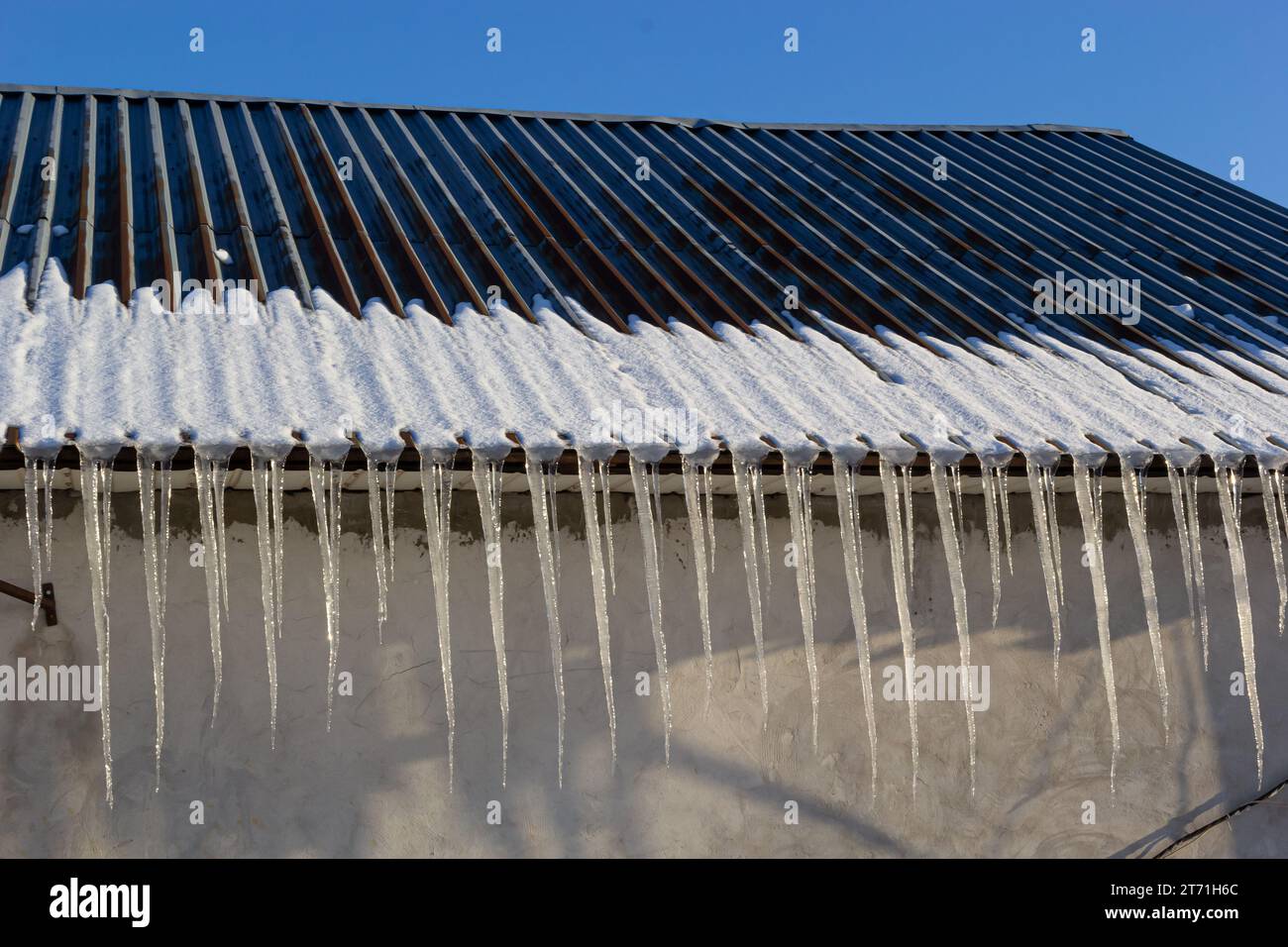 Sharp icicles and melted snow hanging from eaves of roof. Beautiful ...