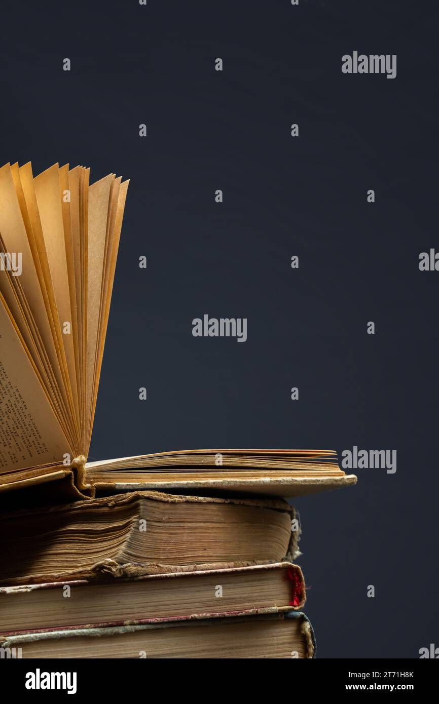 stack of old books with opened one on top on dark background. Old books ...