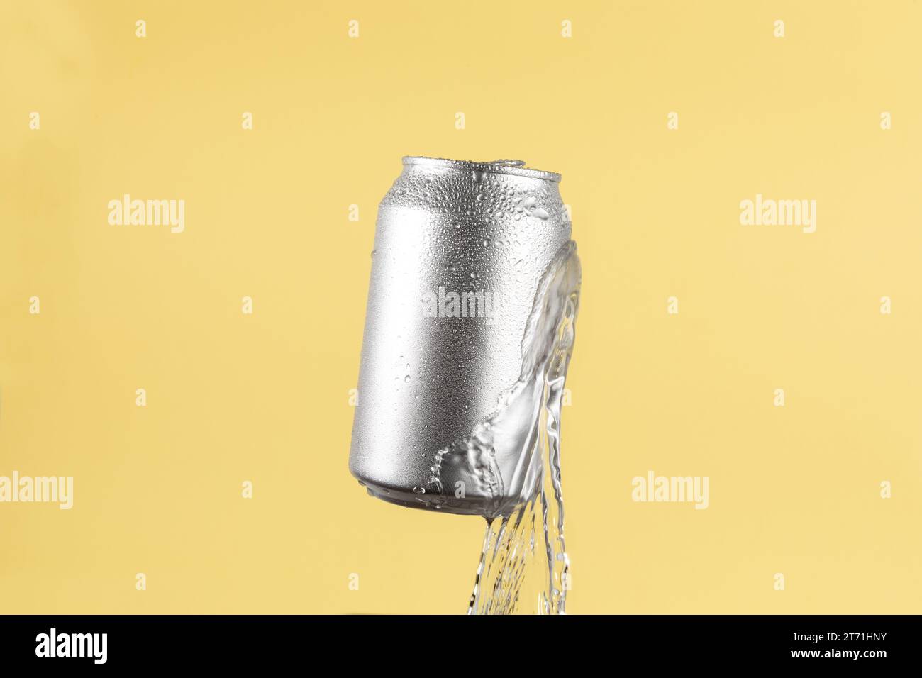 Aluminium beer or soda drinking can with water splash on light yellow ...