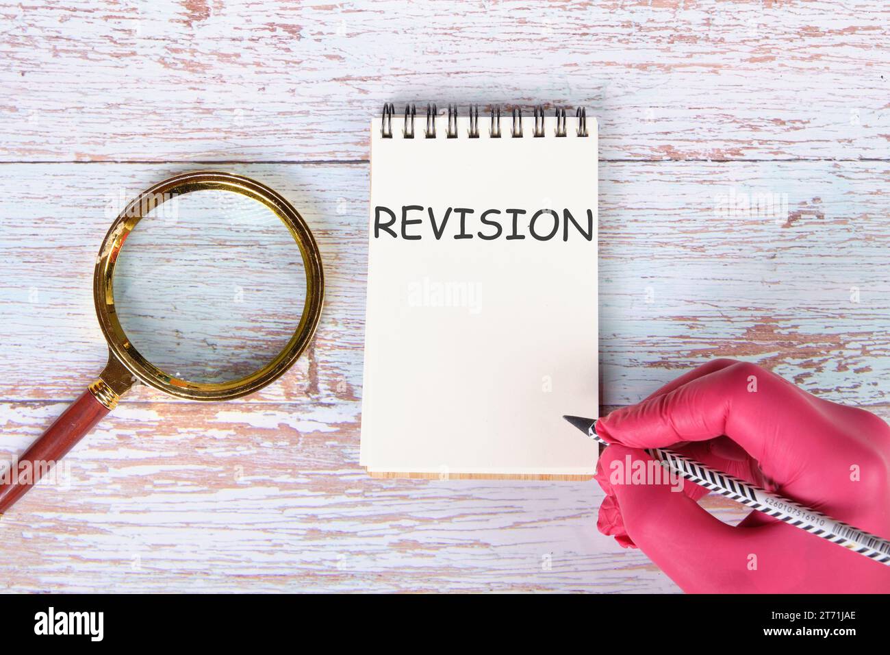 REVISION writing on a notebook lying on old boards next to a magnifying ...