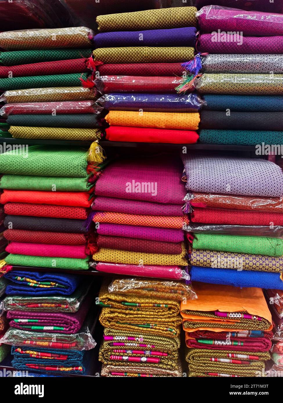 Neatly stacked colorful silk saris in racks in a textile shop, These ...