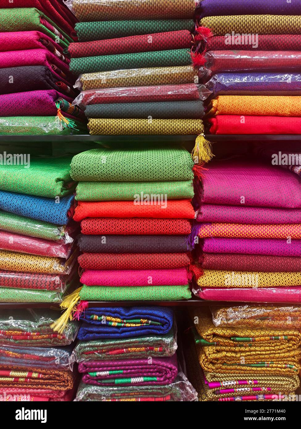 Neatly stacked colorful silk saris in racks in a textile shop, These ...