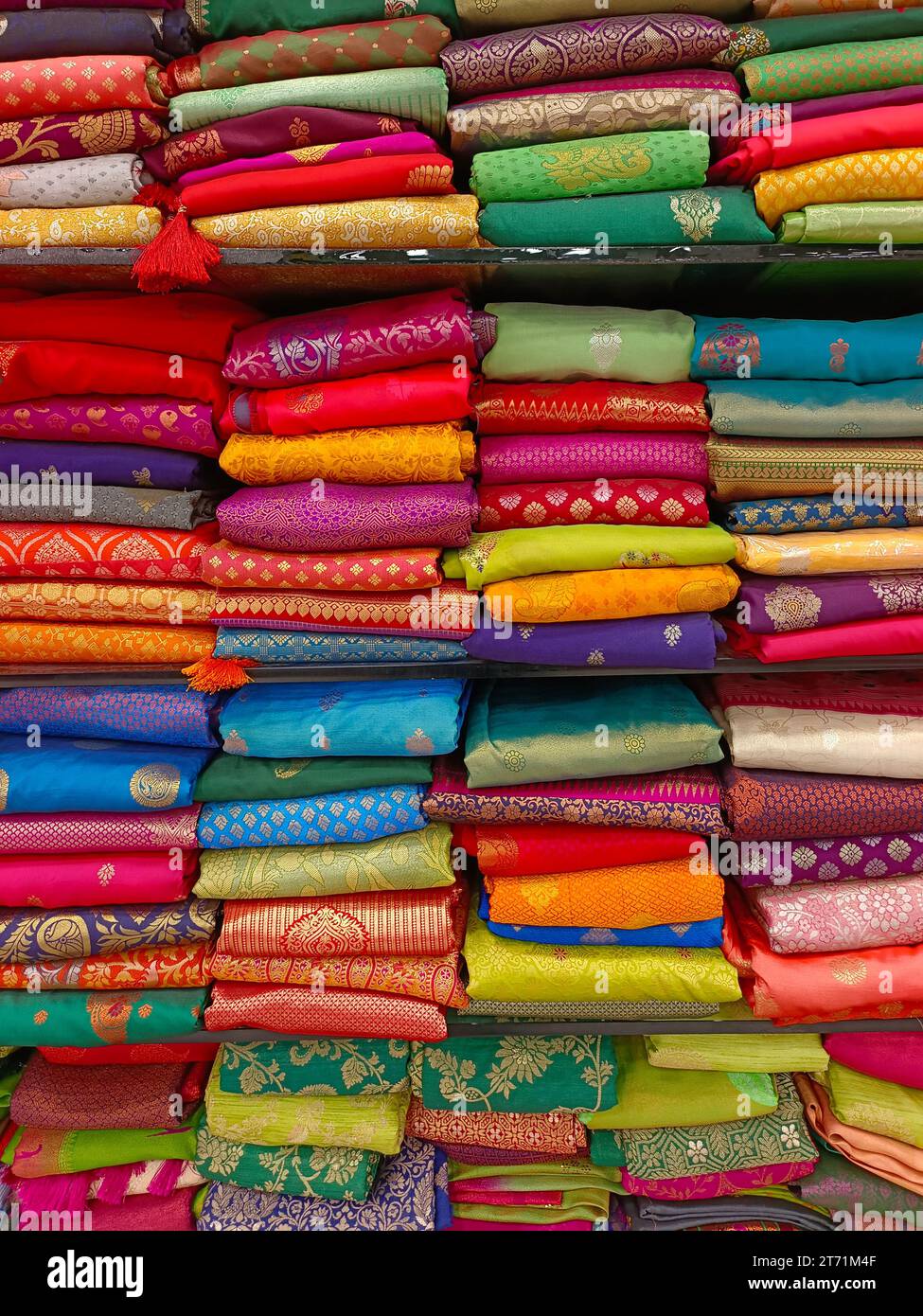 Neatly stacked colorful silk saris in racks in a textile shop, These ...