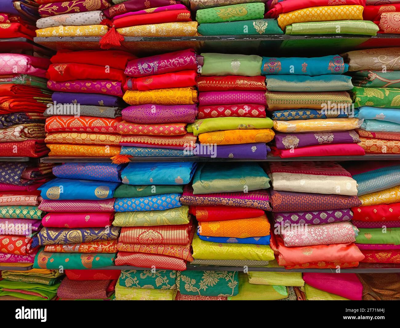 Neatly stacked colorful silk saris in racks in a textile shop, These ...