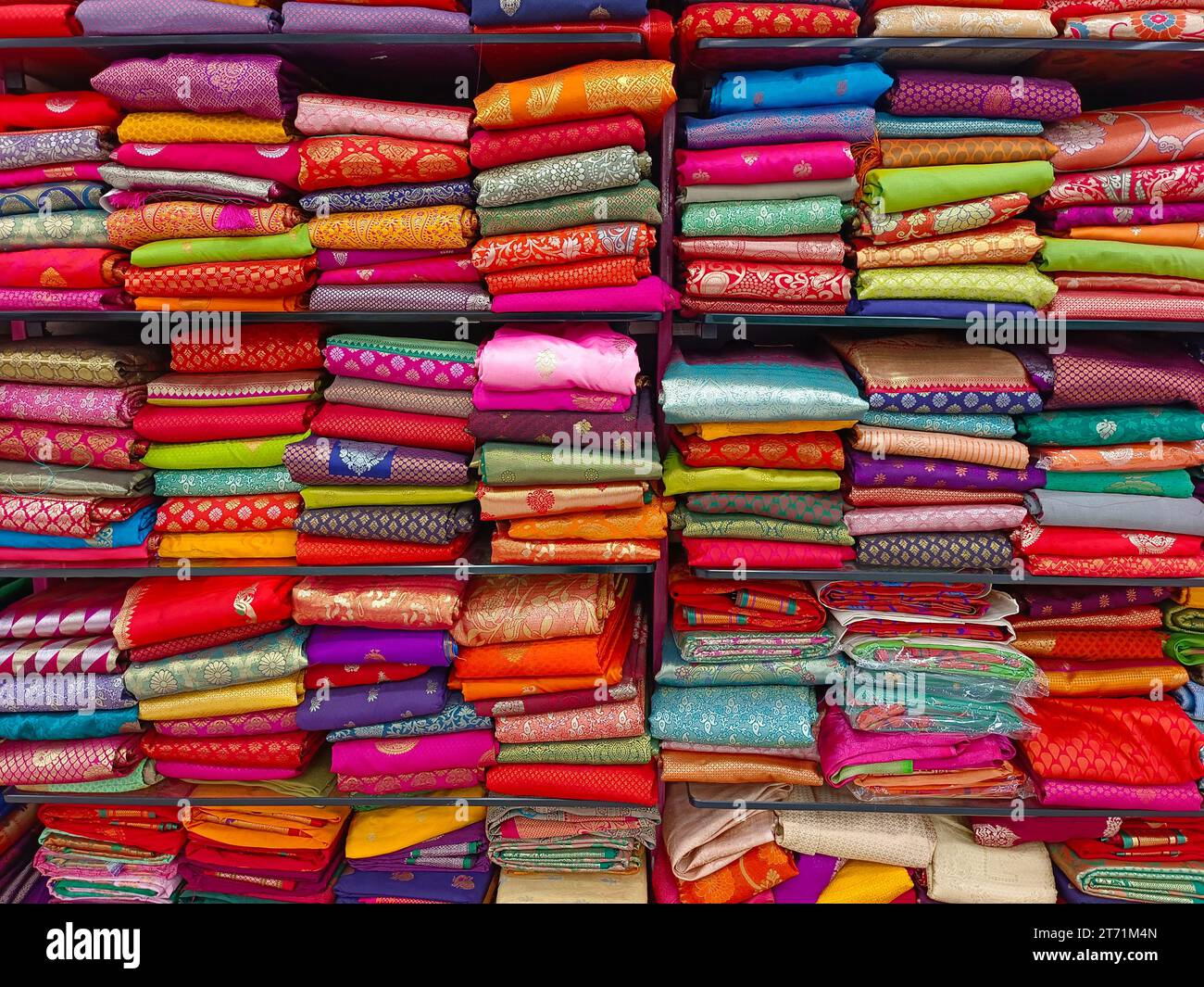 Neatly stacked colorful silk saris in racks in a textile shop, These ...