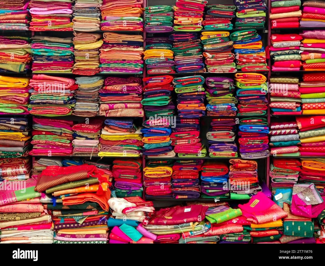 Neatly stacked colorful silk saris in racks in a textile shop, These ...