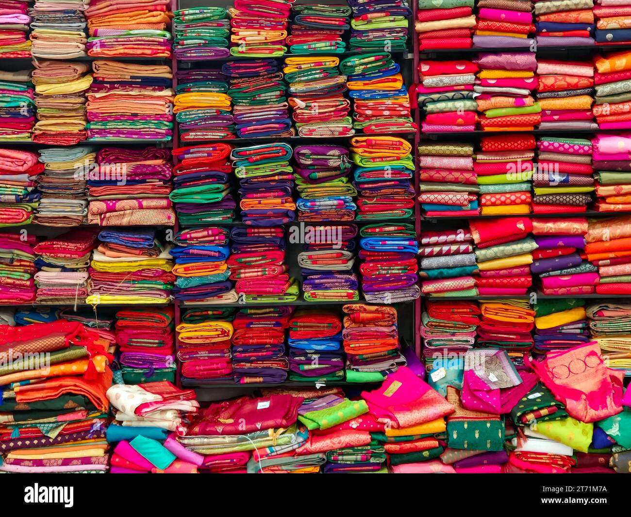 Neatly stacked colorful silk saris in racks in a textile shop, These ...