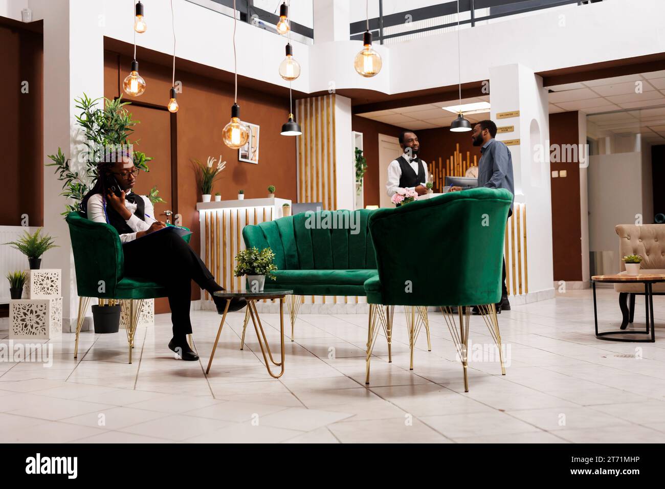 Young African American woman hotel front desk receptionist talking on ...