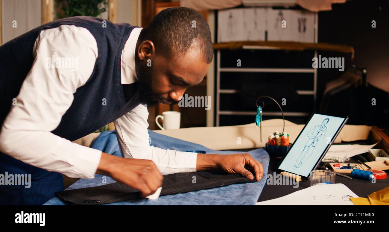 Male couturier marking fabric design to craft fashion items in ...