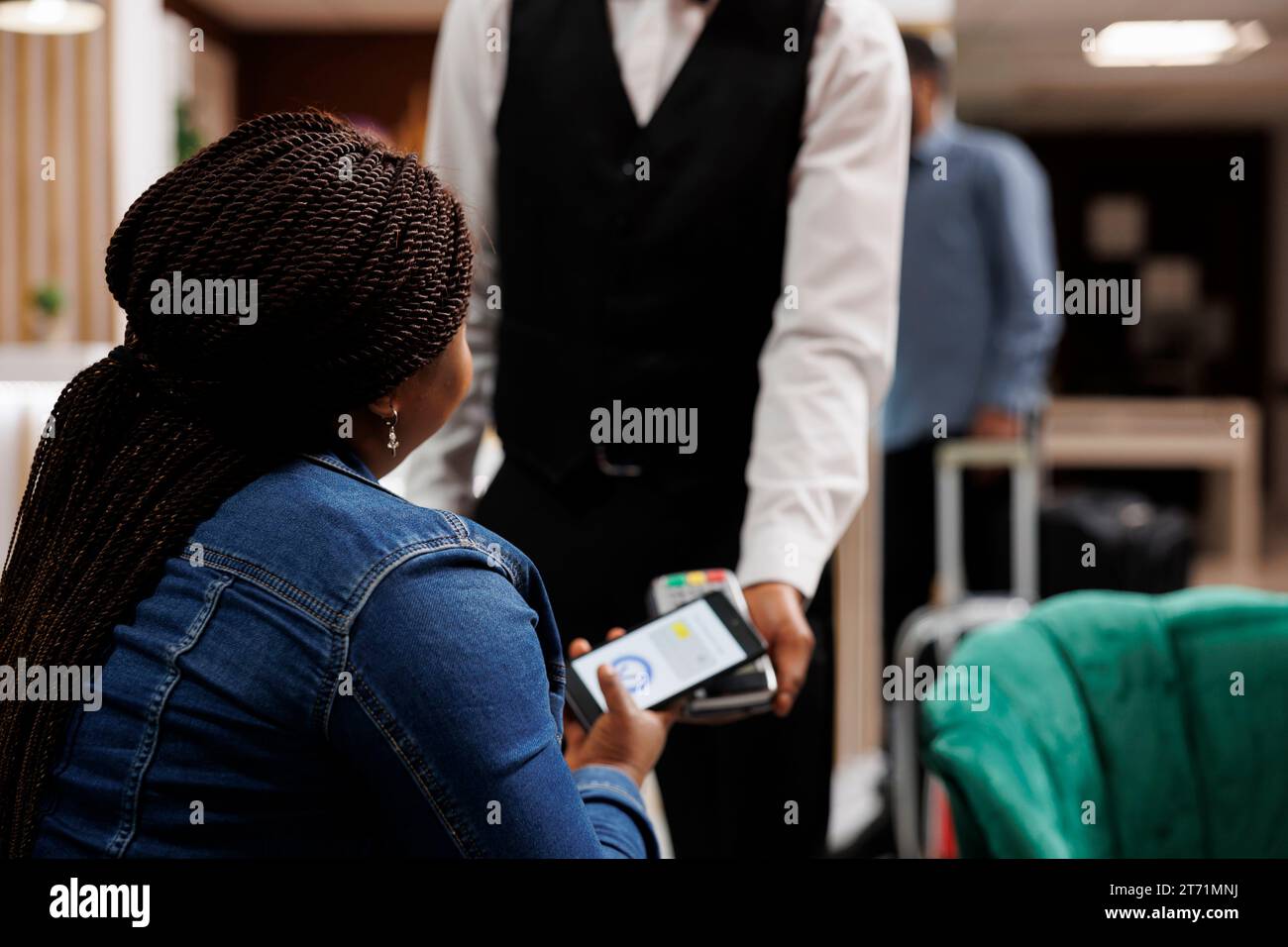 Female hotel guest making cashless payment using smartphone, close up ...