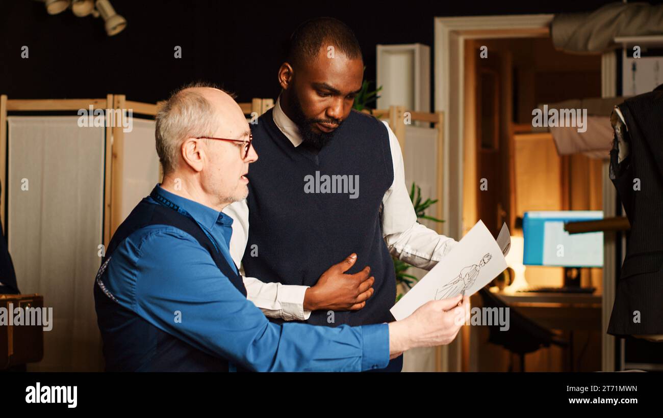 Designer and trainee reviewing drawings in atelier workshop, learning ...