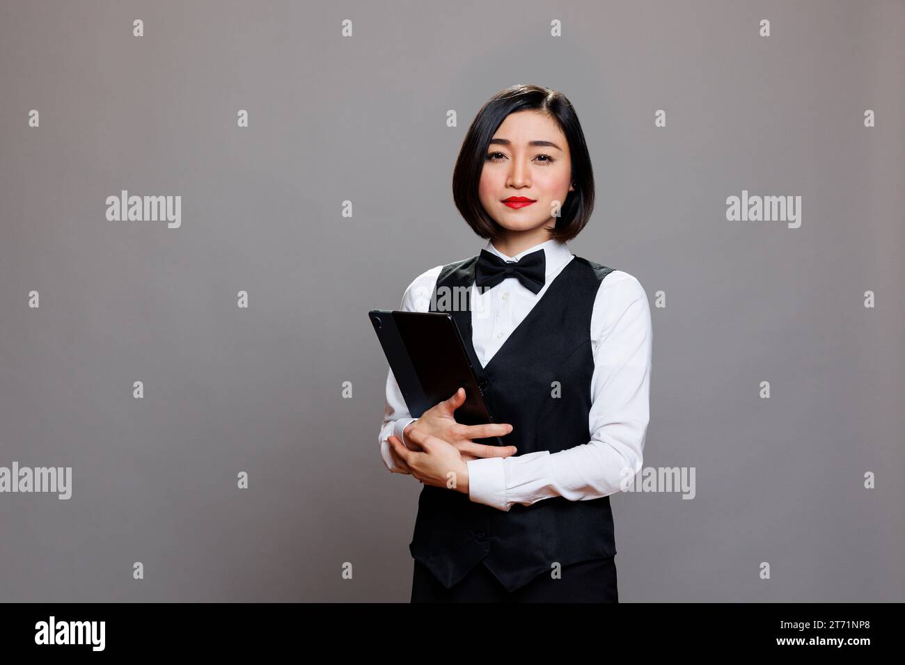 Confident young asian woman waitress wearing uniform and bow tie ...
