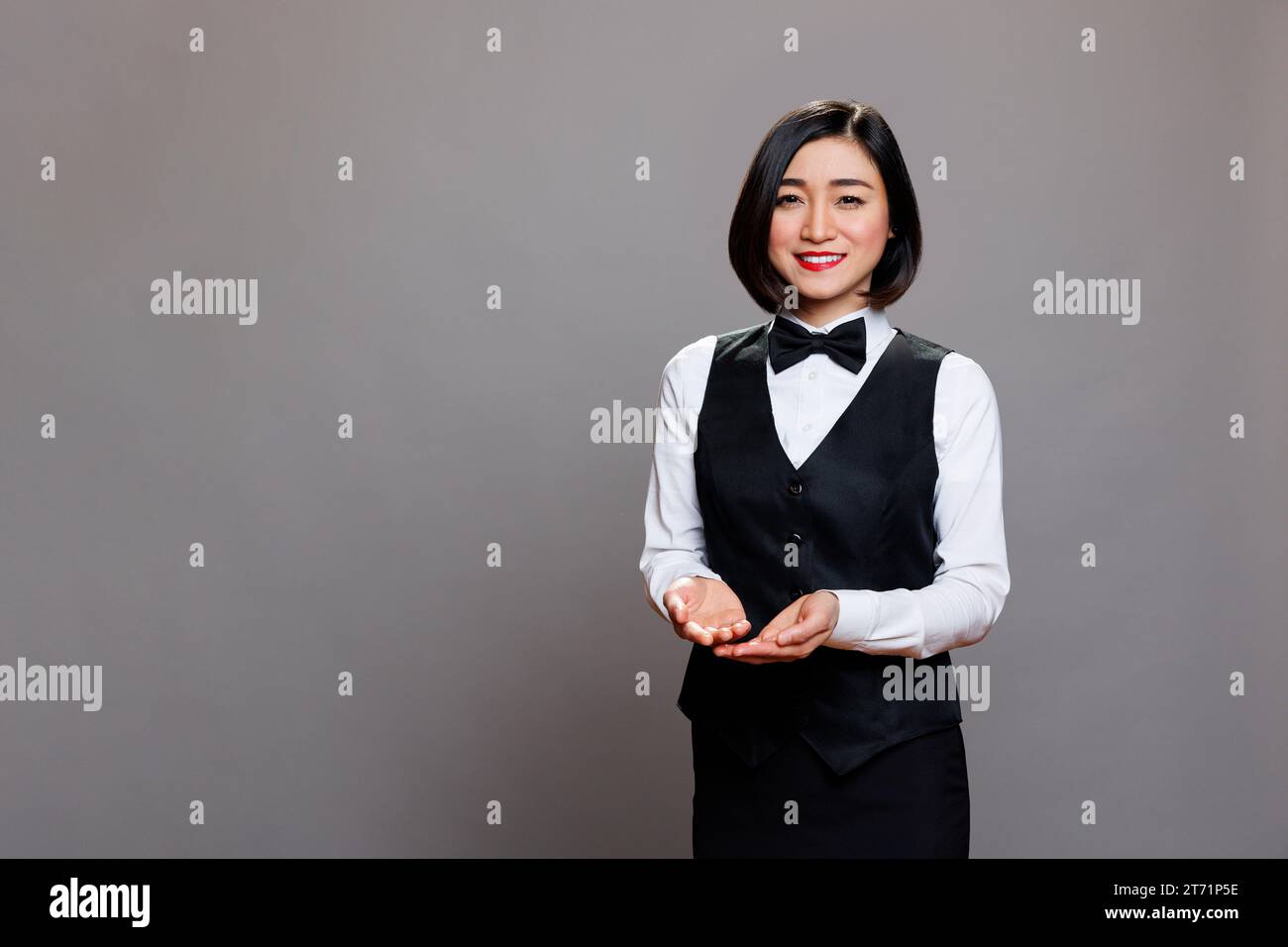 Smiling asian professional waitress showing with hands while looking at ...