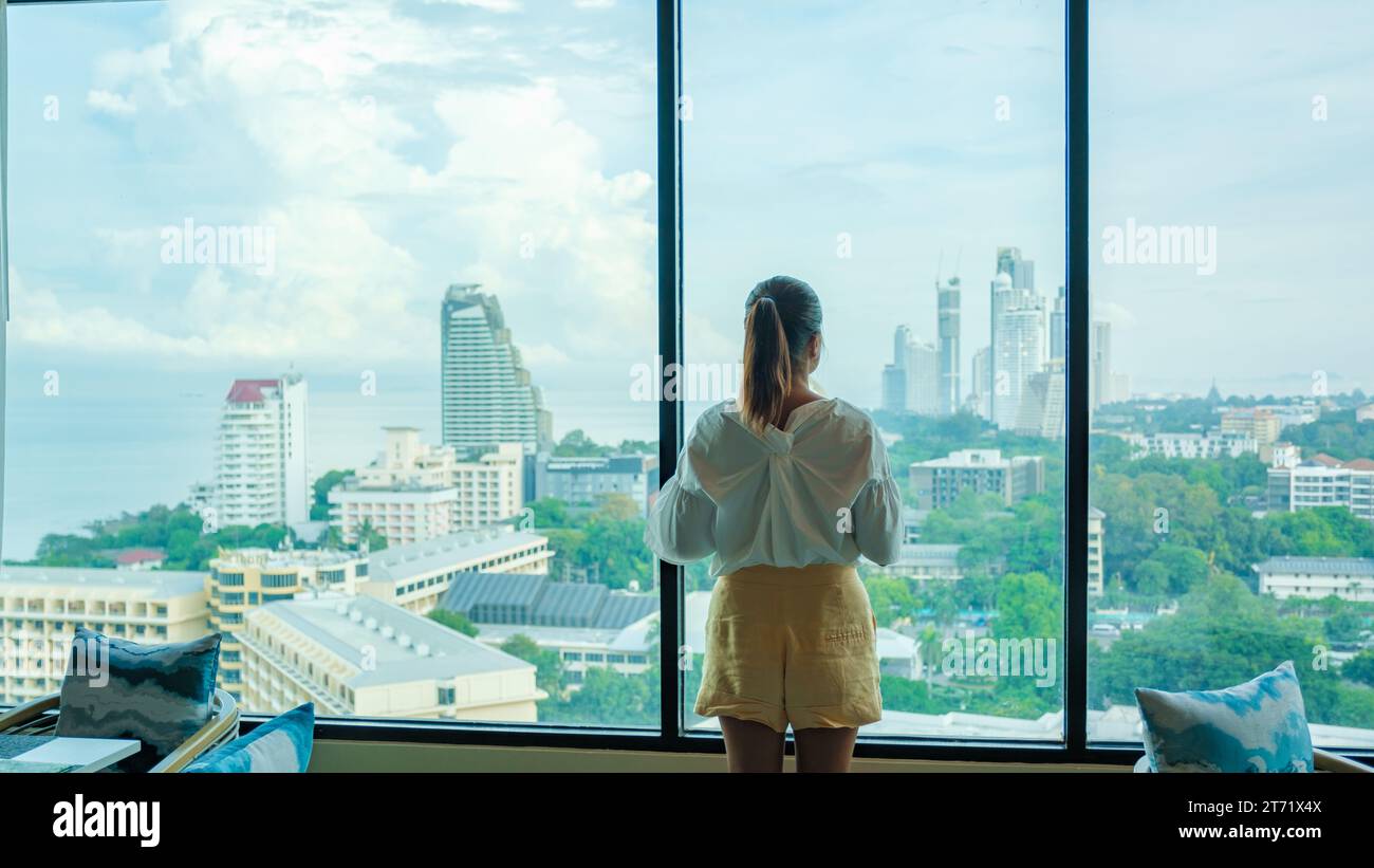 Asian Thai woman drinking coffee in the morning looking out the window ...