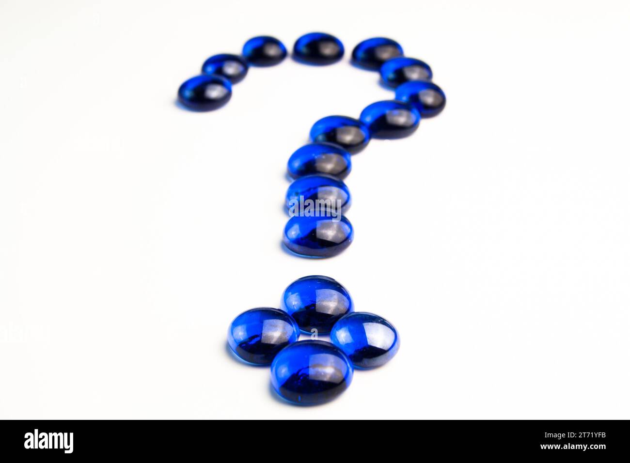 Detail view of question mark drawn with blue stones on white background ...